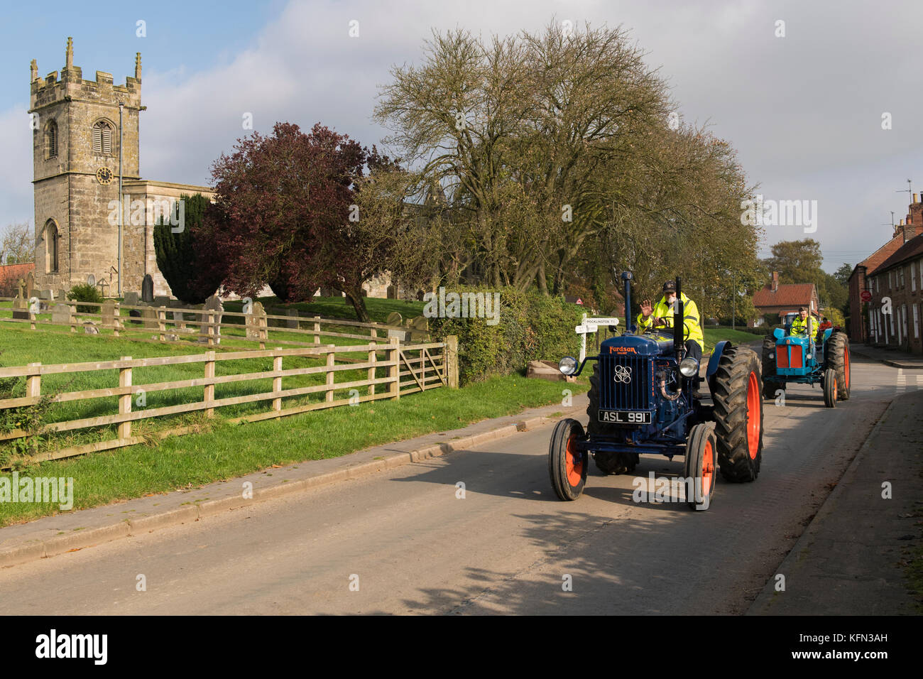Man driving old blue vintage tractor through village of Bugthorpe on ...