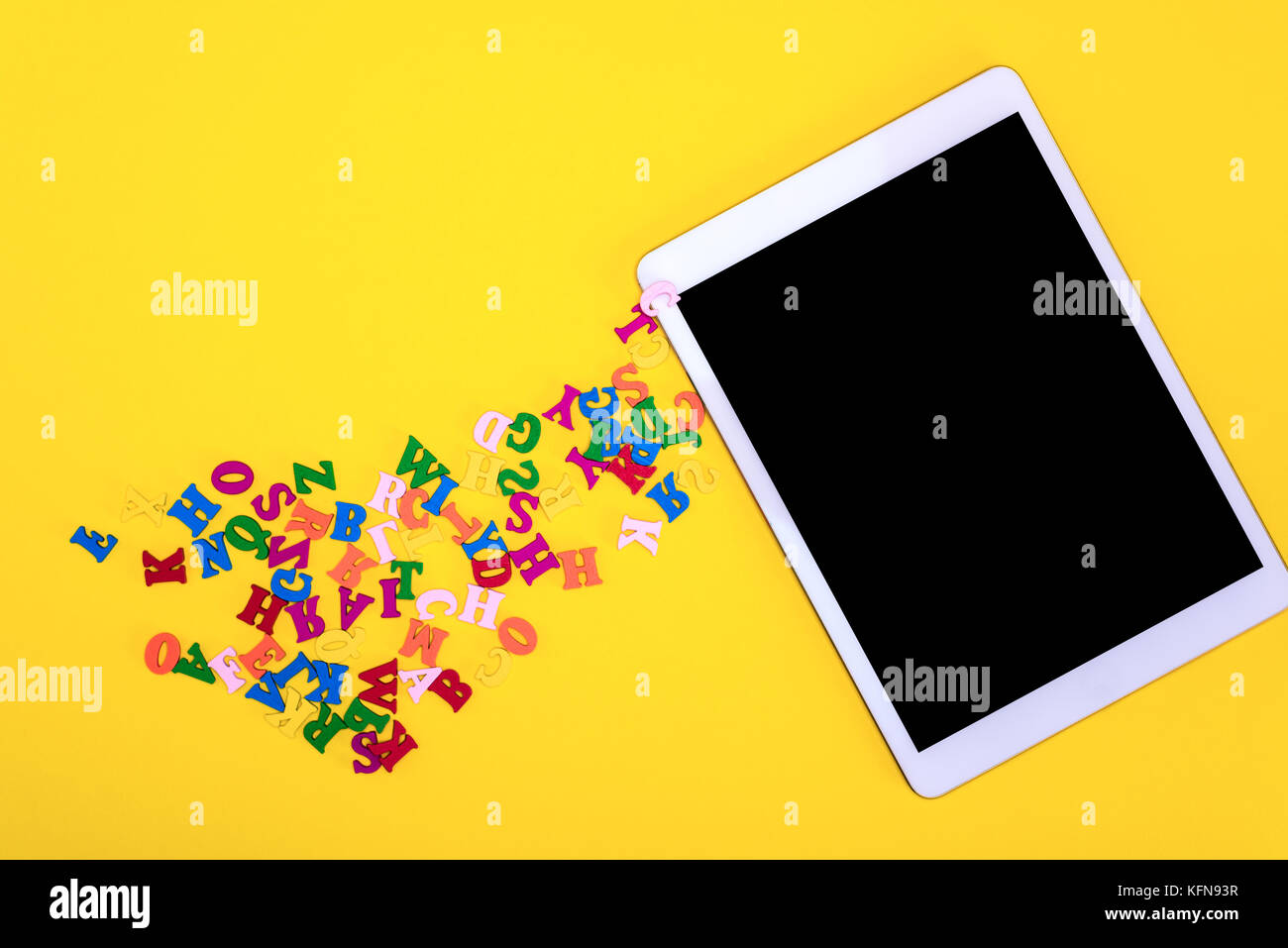 multicolored wooden letters and electronic tablet with a black screen ...
