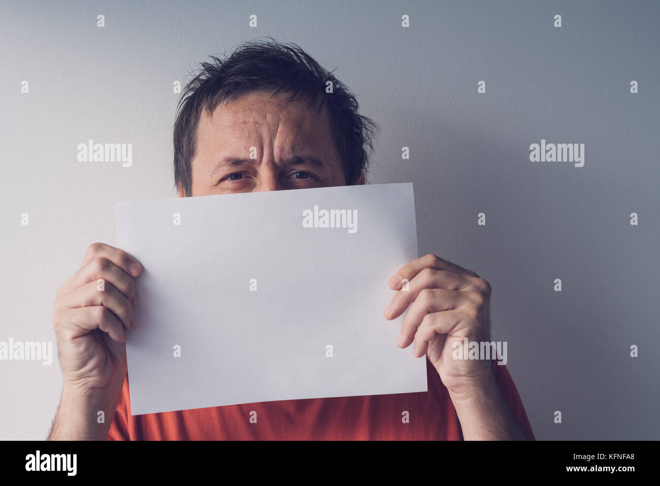 Man hiding behind blank white paper as copy space for text message ...