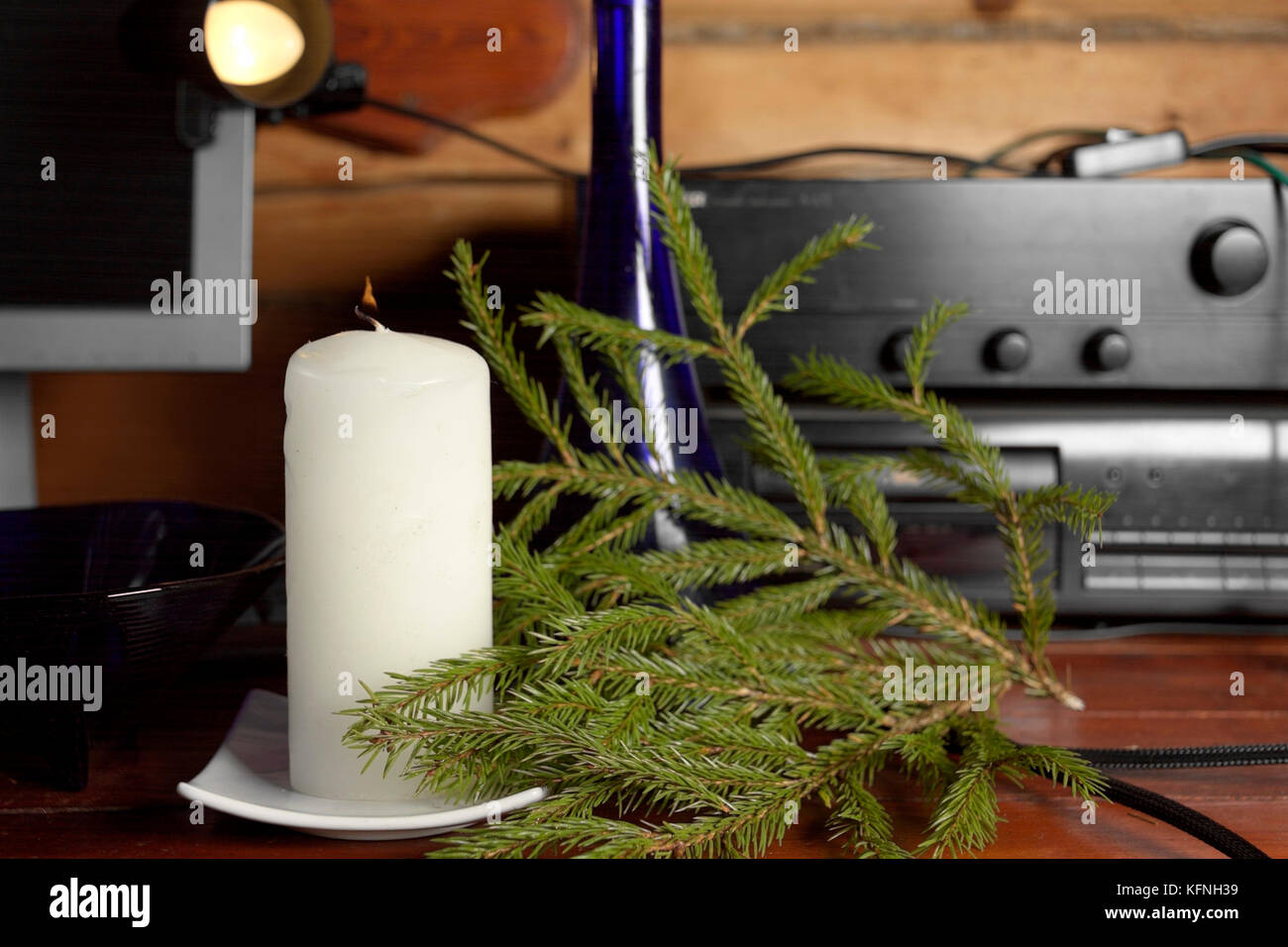A candle, pine tree branch and stereo player in the background. Indoor ...