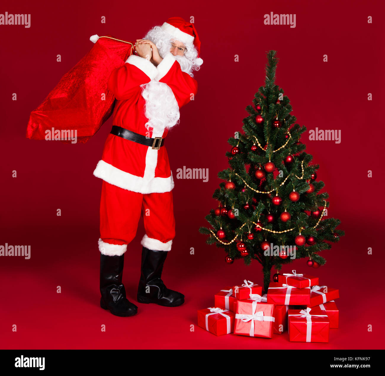 Portrait of santa carrying gifts in sack on red background Stock Photo ...