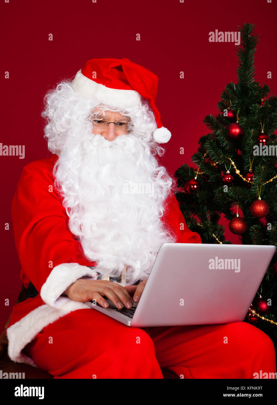Portrait of santa using laptop over red background Stock Photo - Alamy