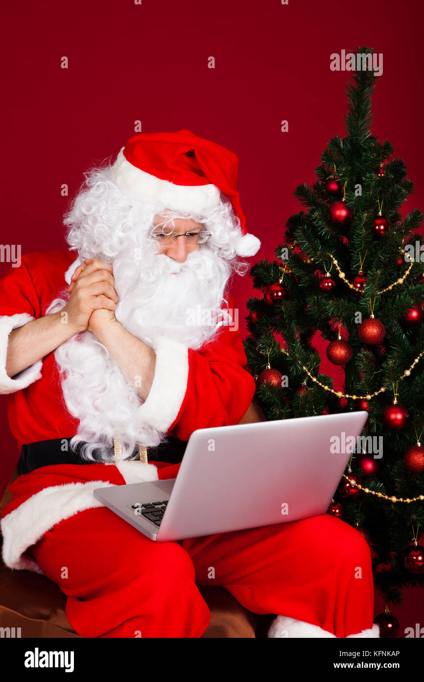 Portrait of santa looking at laptop over white background Stock Photo ...