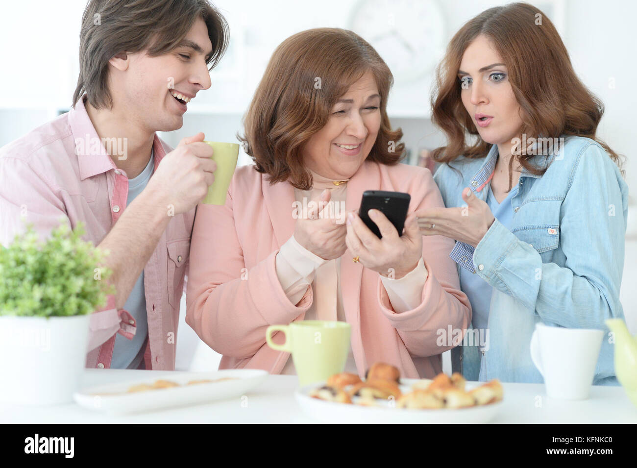 Happy family using mobile phone together Stock Photo - Alamy