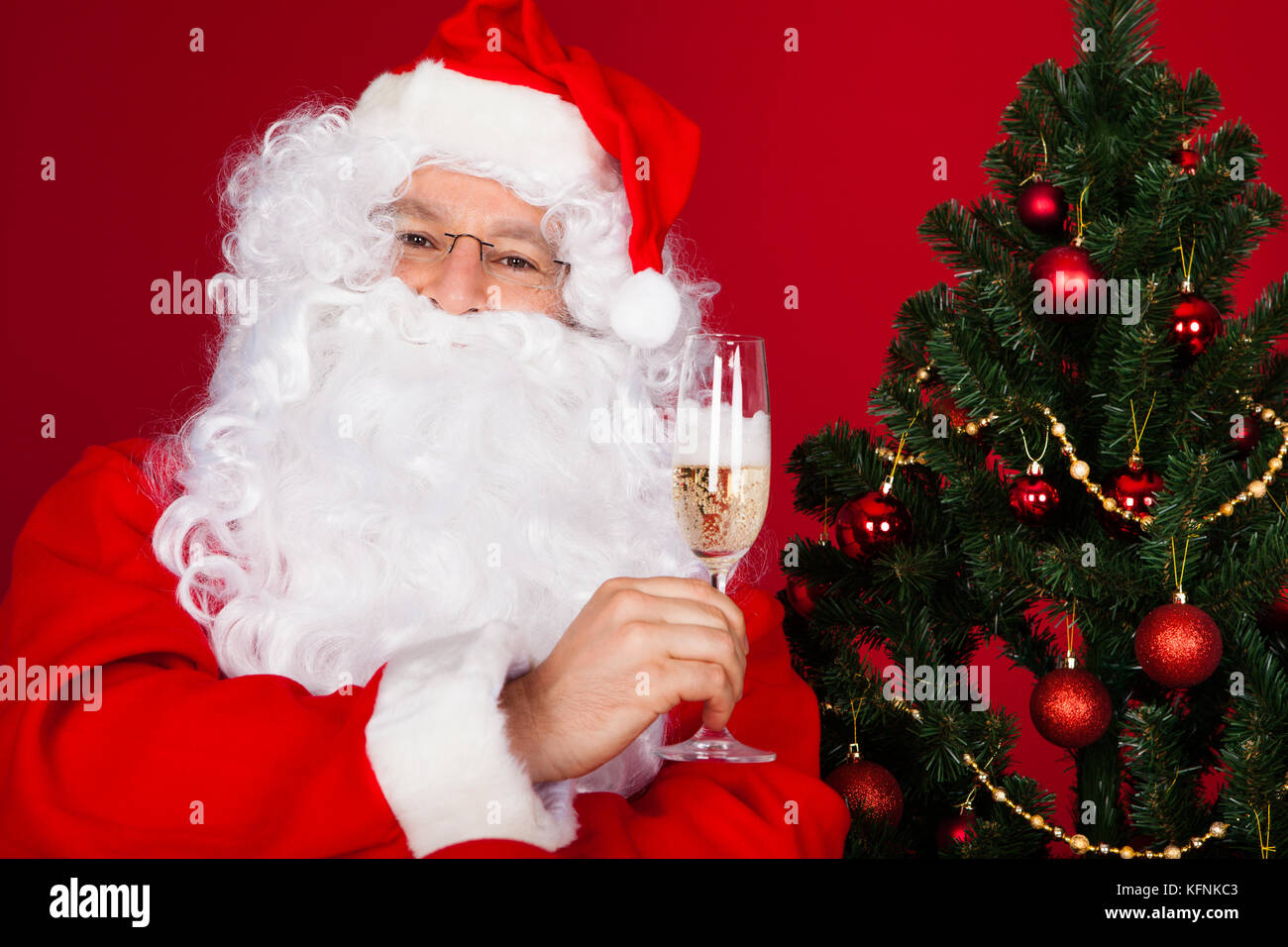 Portrait of a happy santa holding wine glass over red background Stock ...