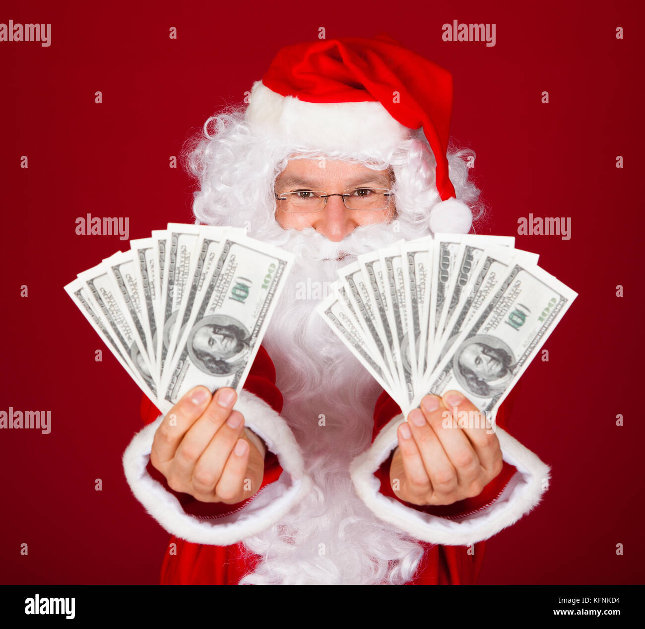 Portrait of happy santa holding dollars over red background Stock Photo ...