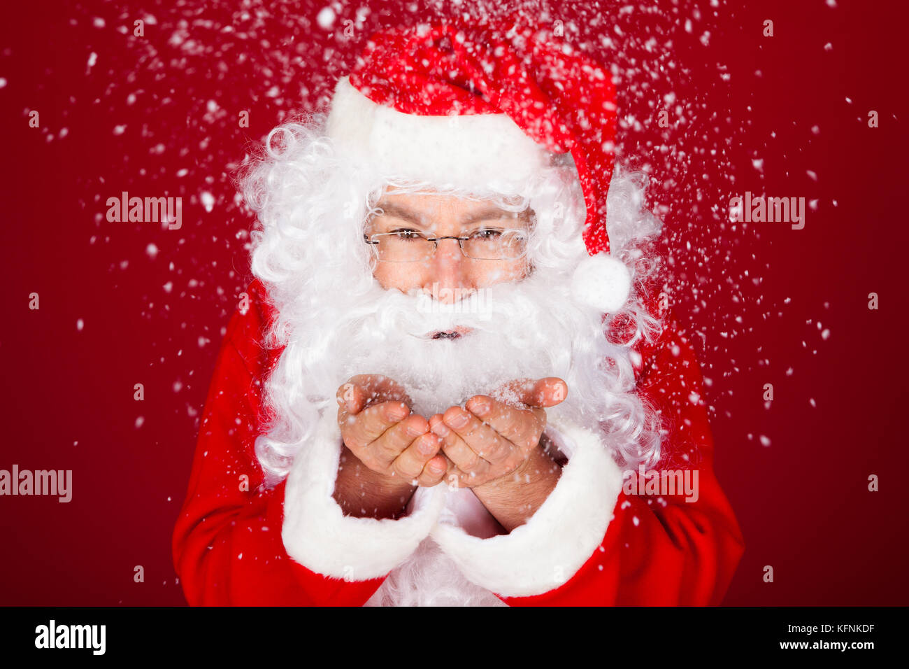 Portrait of santa blowing snow over red background Stock Photo - Alamy
