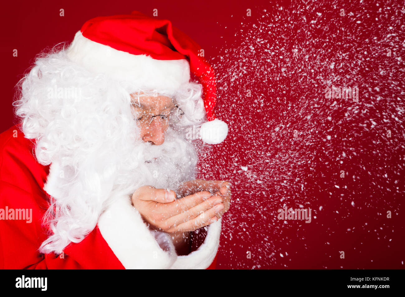 Portrait of santa blowing snow over red background Stock Photo - Alamy