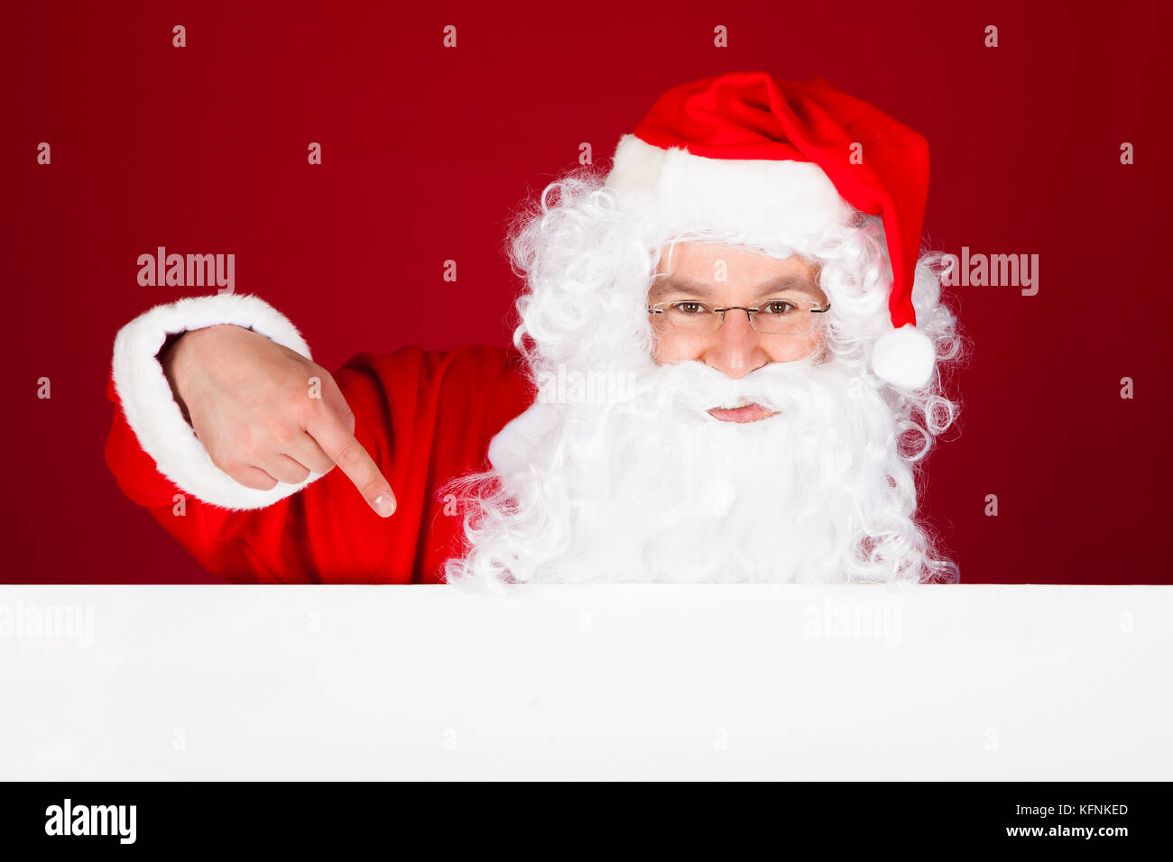 Portrait of a santa holding blank placard over red background Stock ...