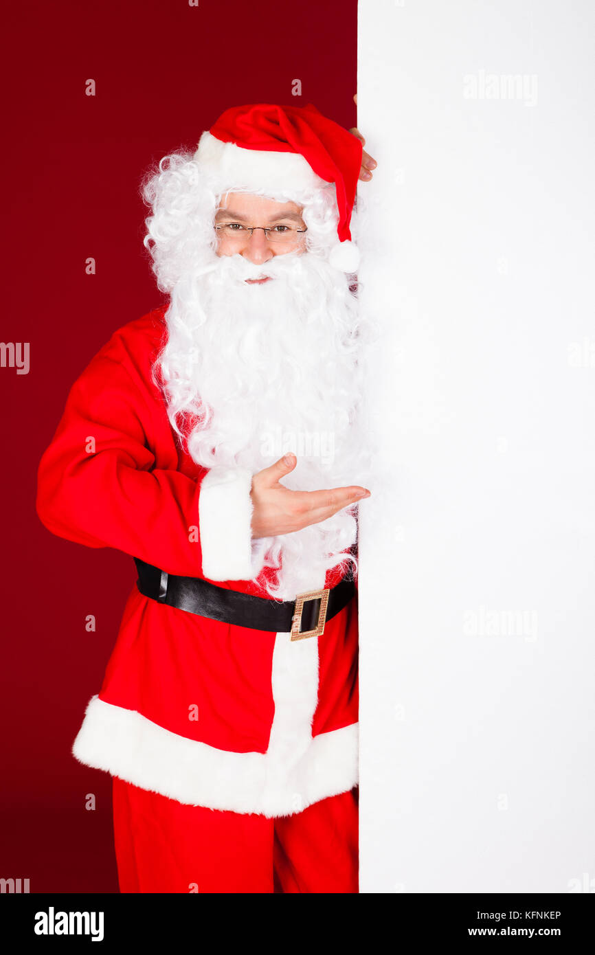 Portrait of a santa holding blank placard over red background Stock ...