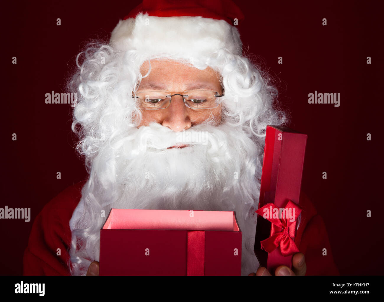 Close-up of santa looking in gift over black background Stock Photo - Alamy