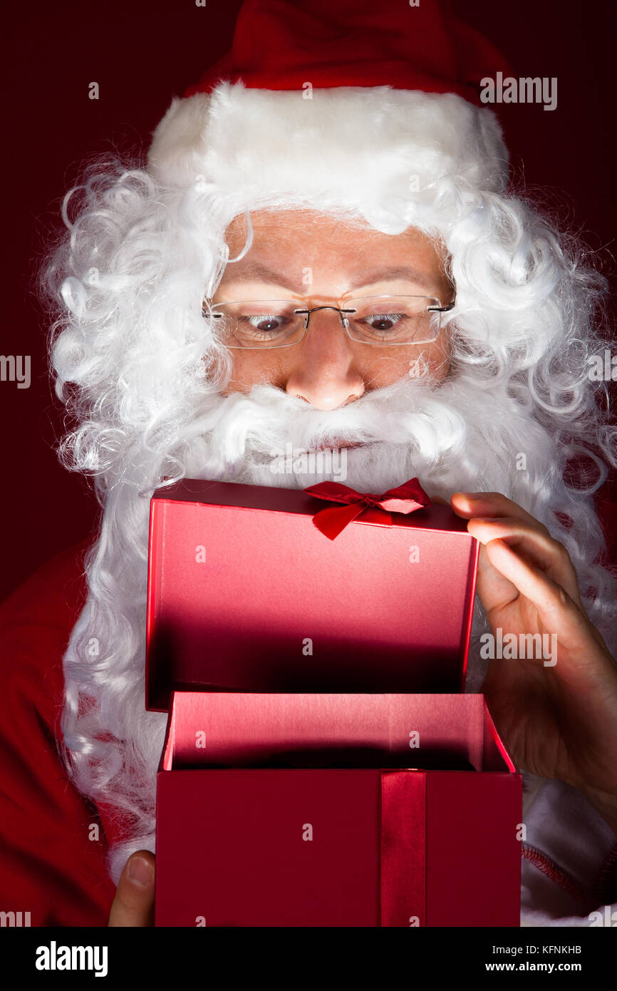 Close-up of santa looking in gift over black background Stock Photo - Alamy