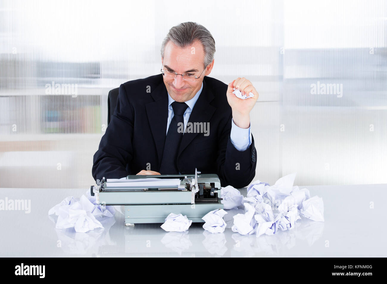 Portrait of happy mature businessman typing on typewriter Stock Photo ...