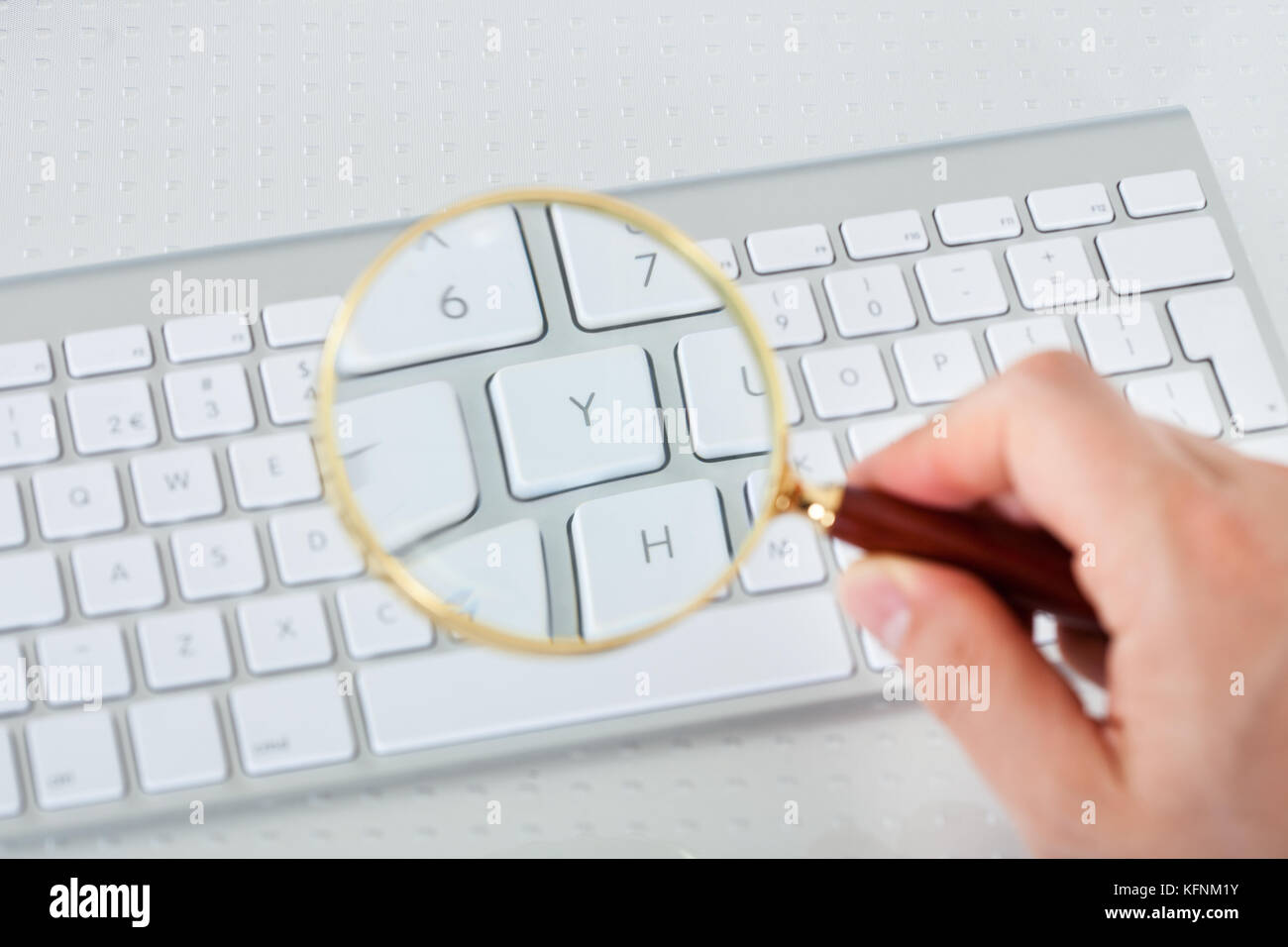 Close-up of hand looking at keyboard key through magnifying glass Stock ...