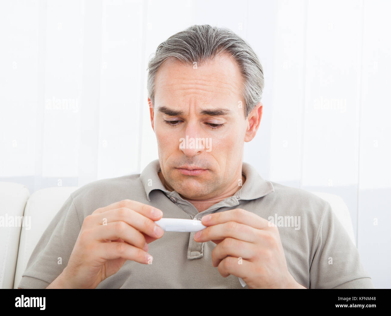 Portrait of a sick man looking at thermometer Stock Photo - Alamy