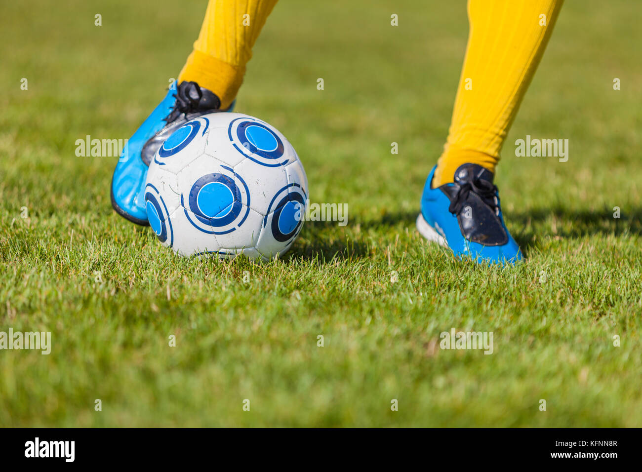 Close-up image of the feet of a footbal player kicking the ball. Focus ...