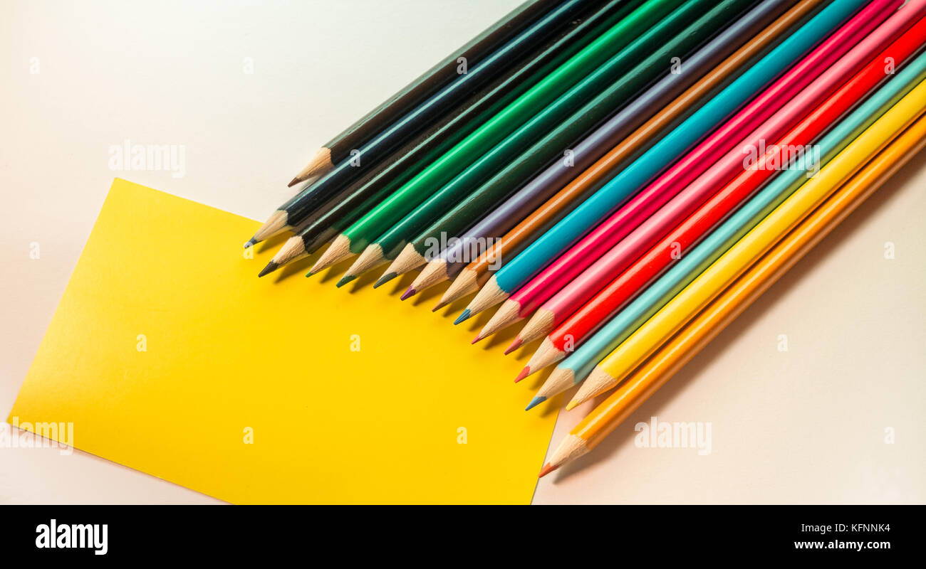 Colored Pencils isolated on white backdrop and blank Yellow note ...