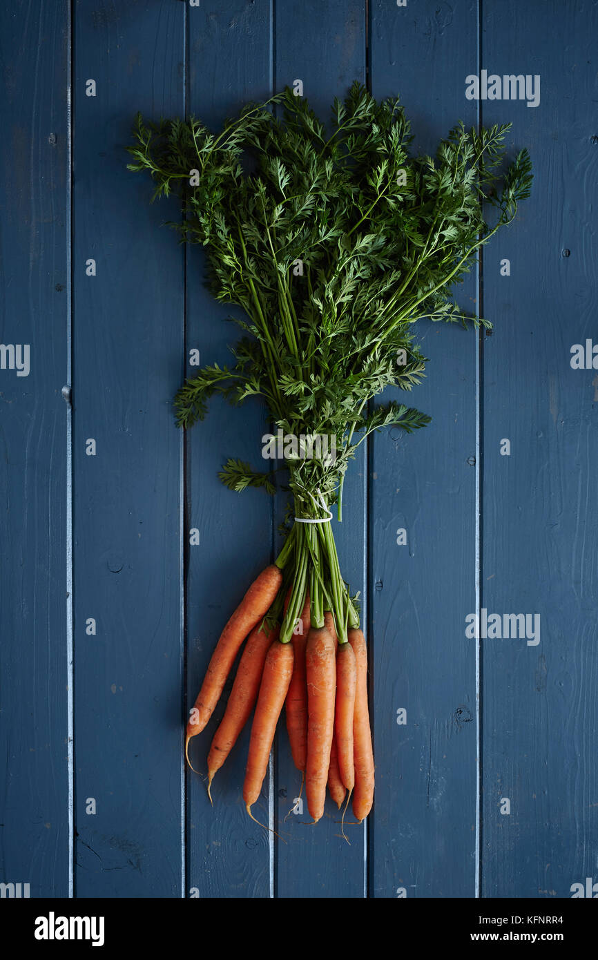 Bund Karotten auf blauem vintage Tisch Stock Photo - Alamy