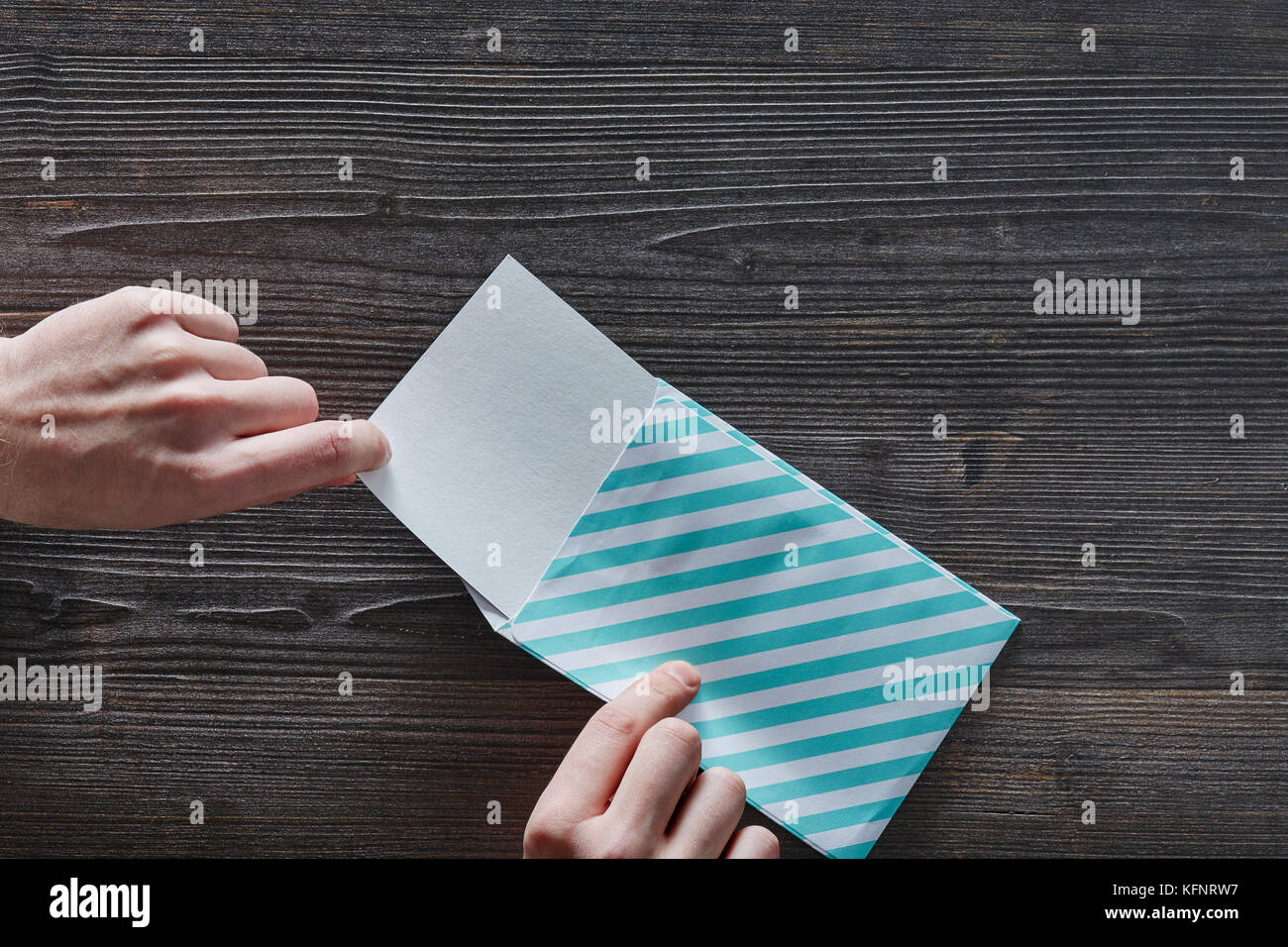 two hands opening a striped letter on wooden table Stock Photo - Alamy