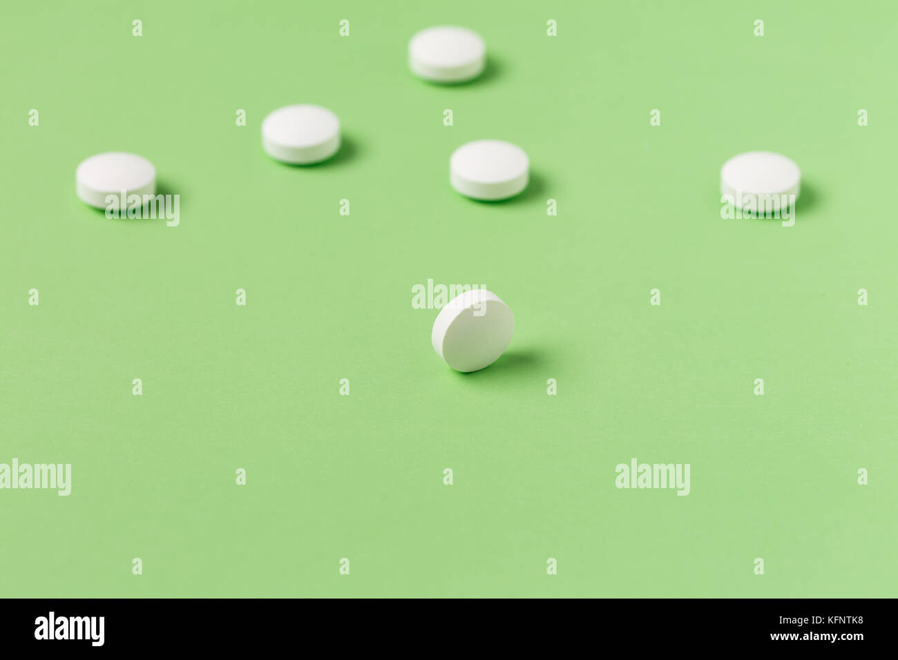 Round white medicine pills on green background Stock Photo - Alamy