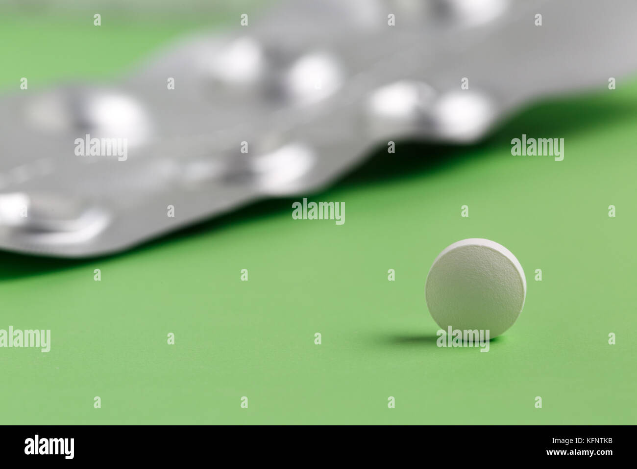 Round white medicine pills on green background Stock Photo - Alamy