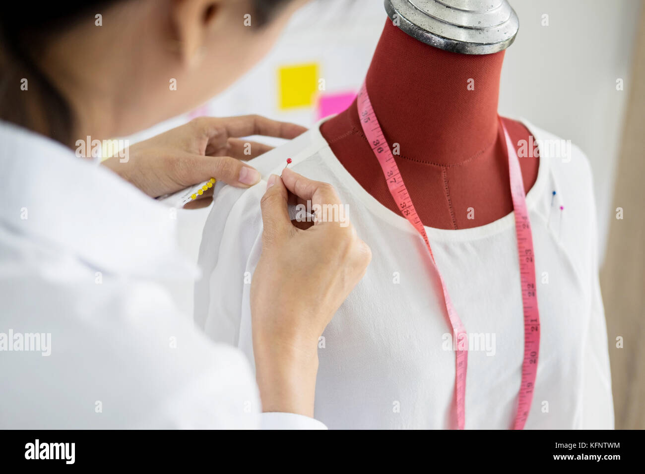 Asian tailor adjusts garment design on mannequin in workshop make a ...