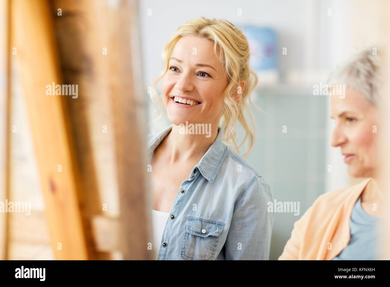artists discussing painting on easel at art school Stock Photo - Alamy