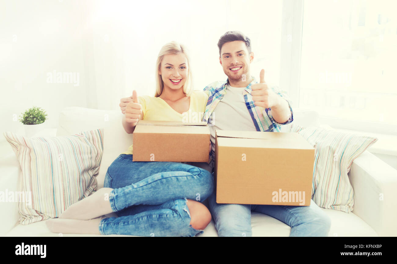 happy couple with boxes showing thumbs up at home Stock Photo - Alamy