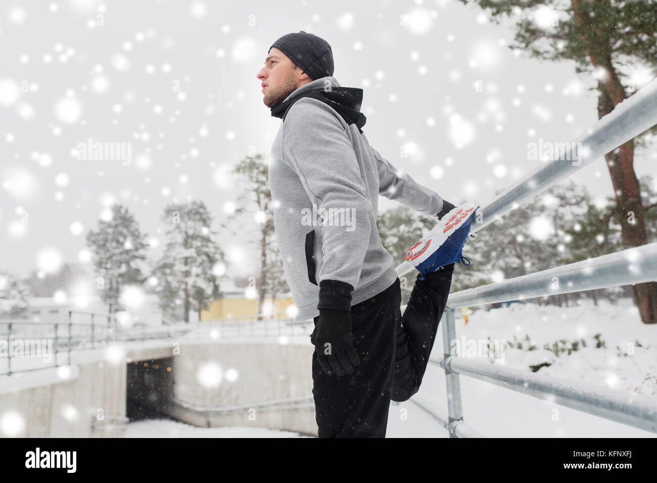 sports man stretching leg at fence in winter Stock Photo - Alamy