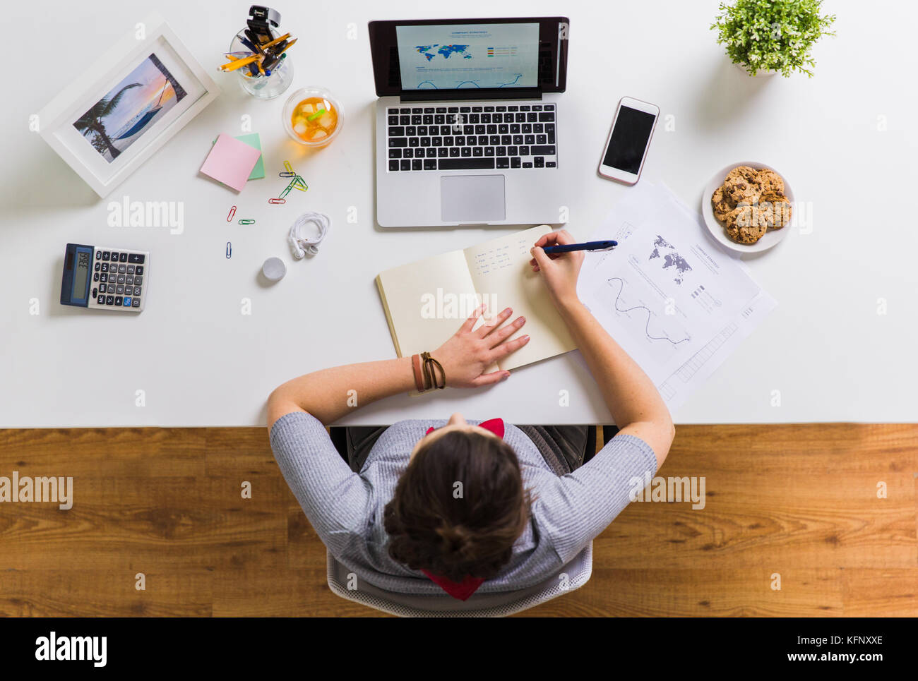 woman with laptop writing to notebook at office Stock Photo - Alamy