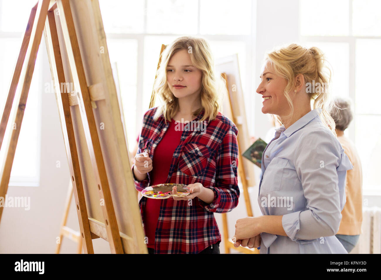artists discussing painting on easel at art school Stock Photo - Alamy