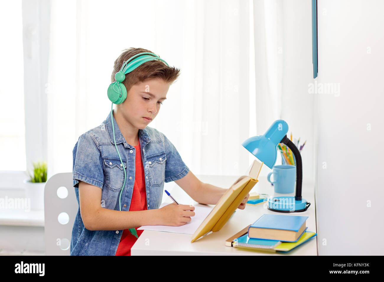 student boy in headphones writing to notebook Stock Photo - Alamy