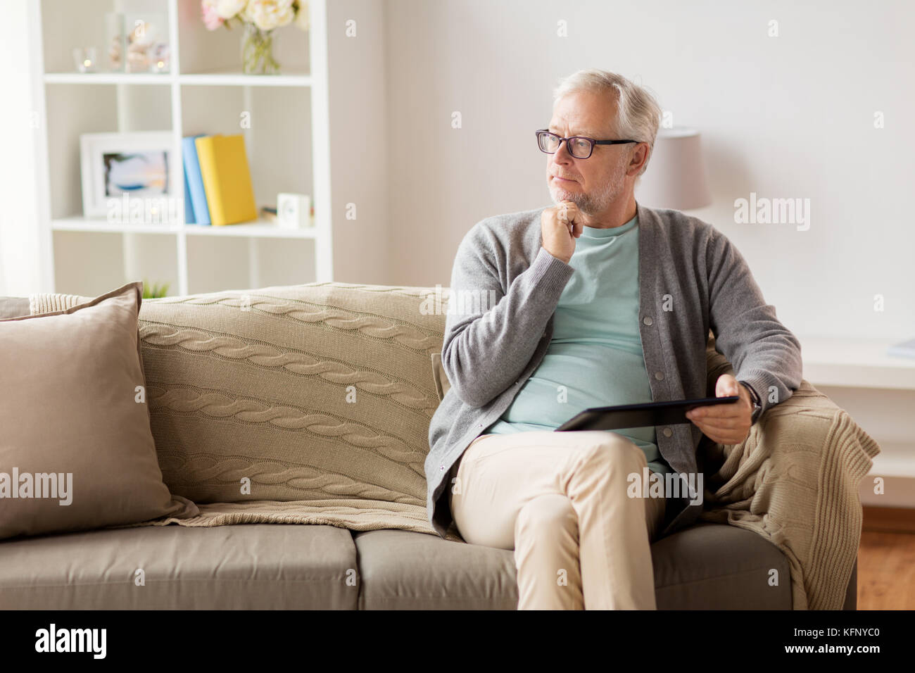senior man with tablet pc sitting on sofa at home Stock Photo - Alamy