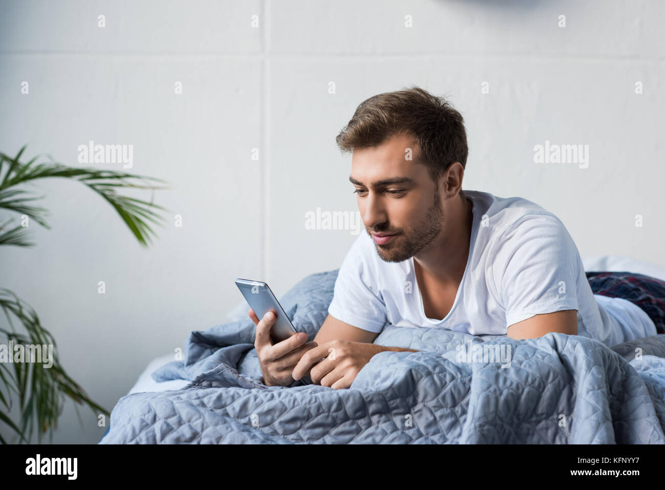 Man in bed using smartphone Stock Photo - Alamy