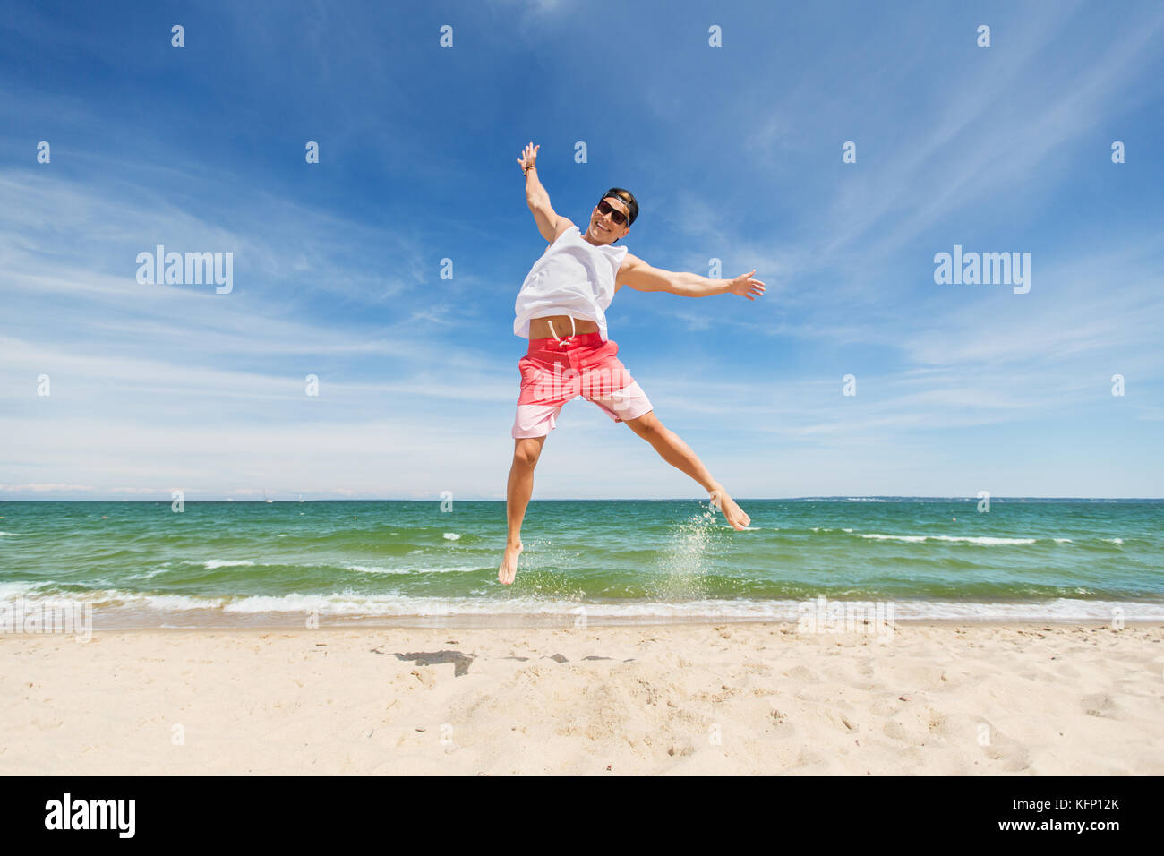 smiling young man jumping on summer beach Stock Photo - Alamy