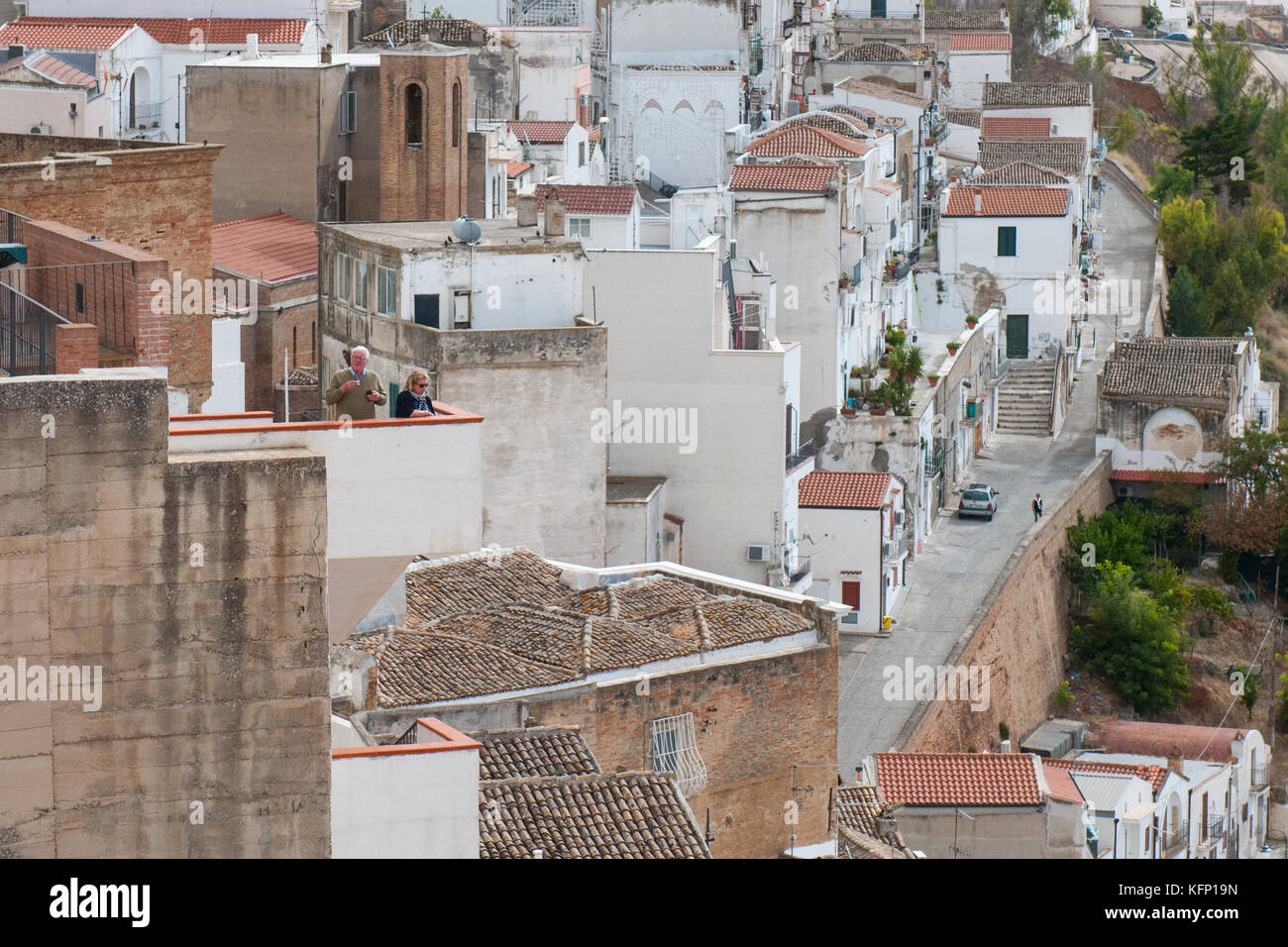 Two tourists look the village of Pisticci, Italy. Pisticci is a town in ...