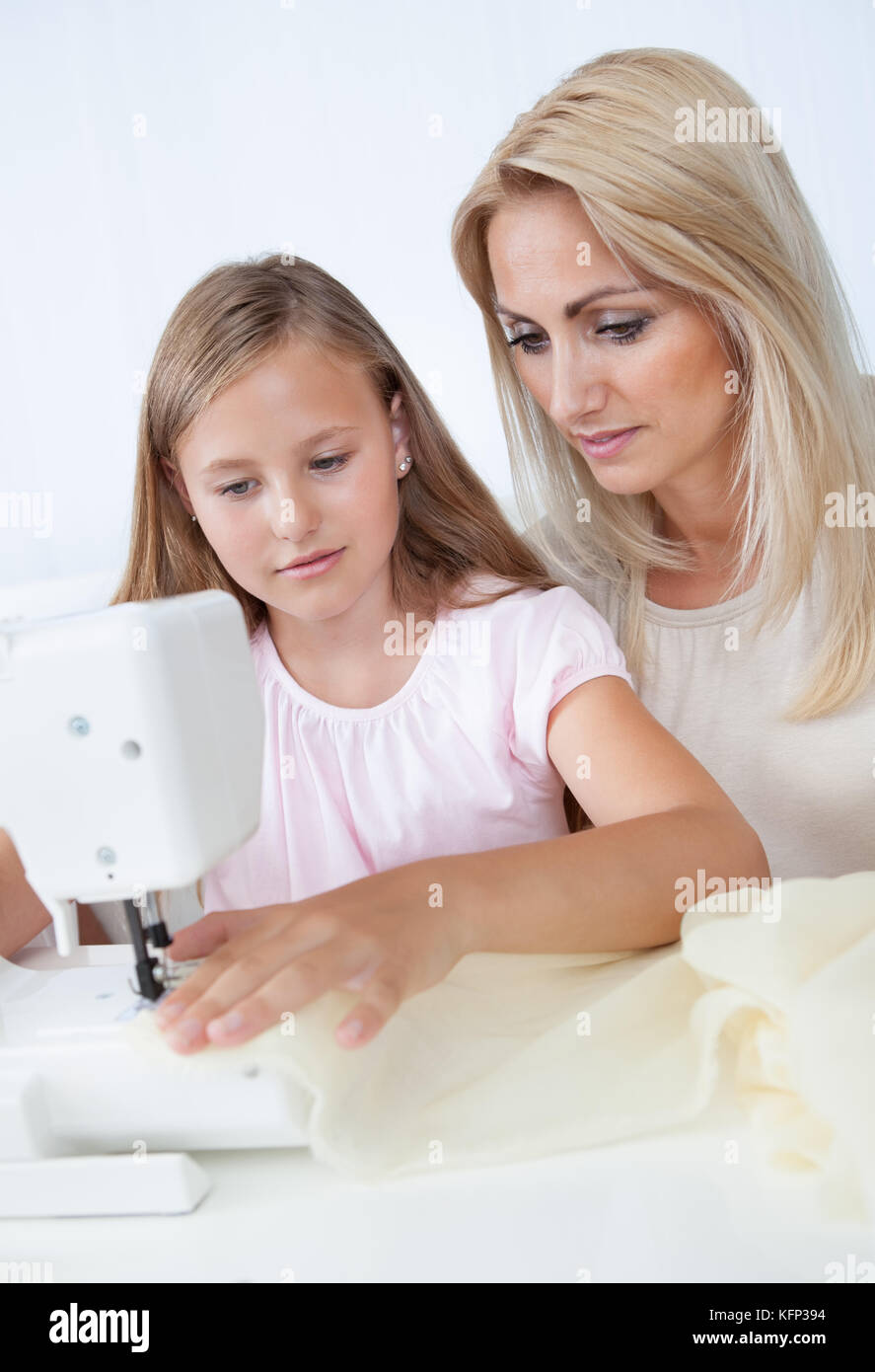 Portrait Of A Beautiful Young Girl Sewing With Her Mother At Home Stock ...