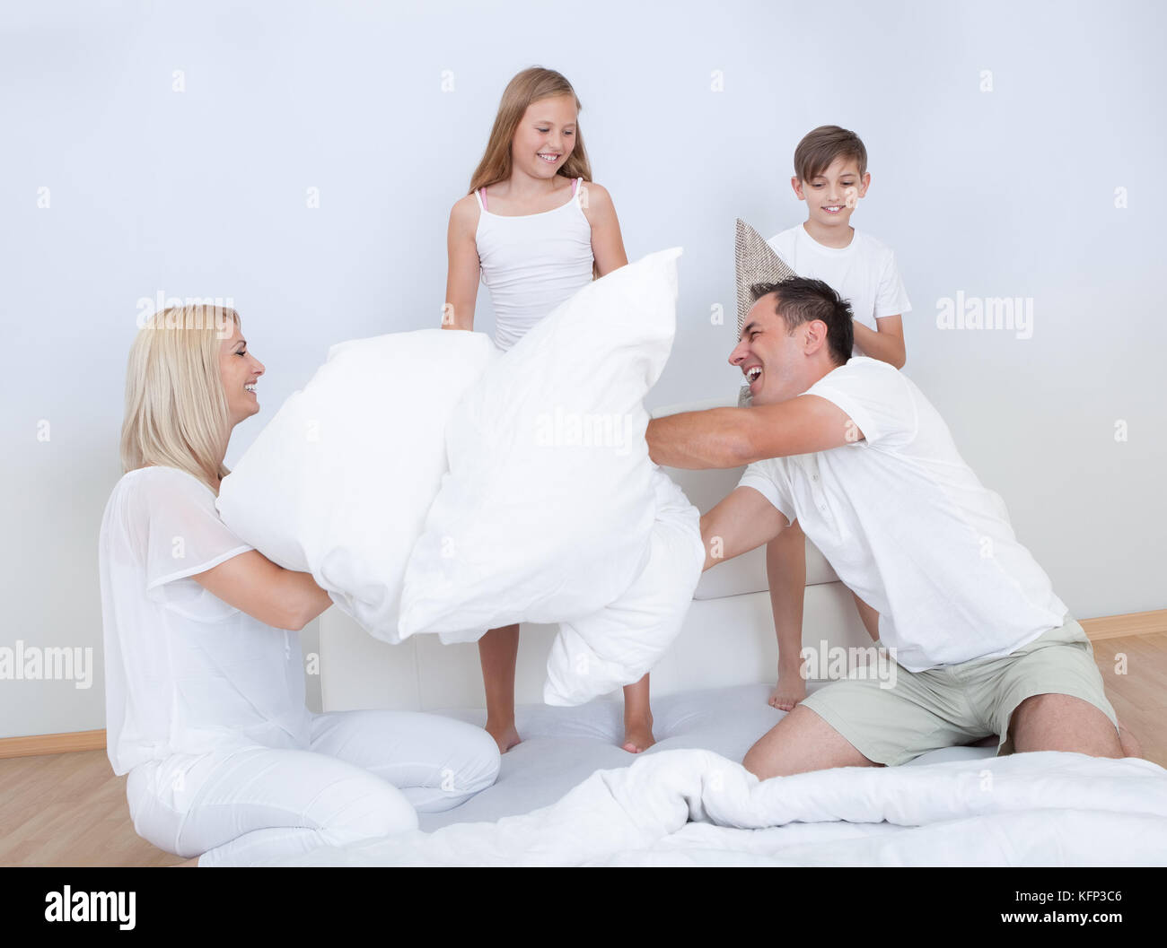 Playful Family Having A Pillow Fight Together On Bed In Bedroom Stock ...