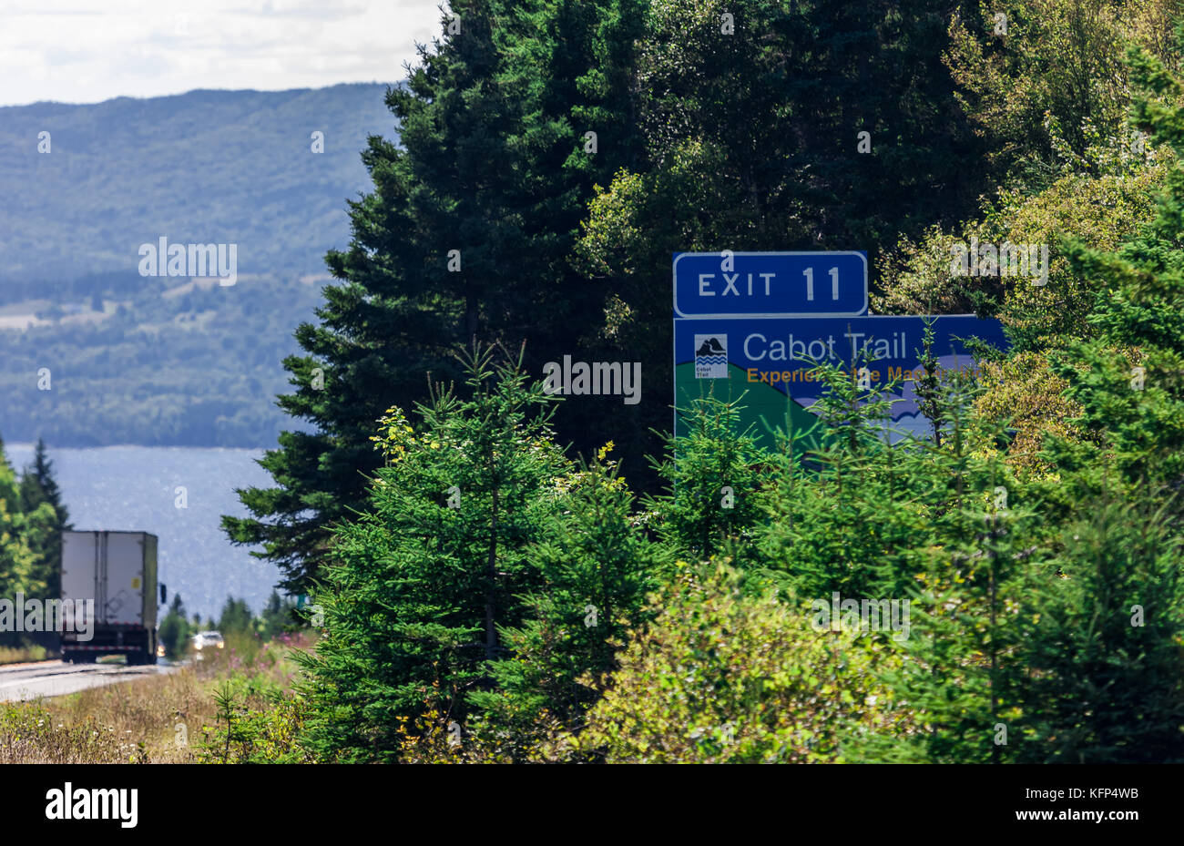 Trucks and cars drive past a road sign leading to the Cabot Trail Stock ...