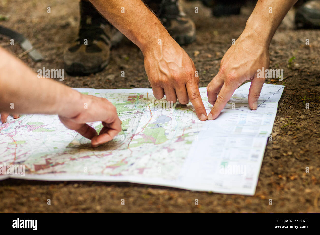 A group of hikers uses map and compass to navigate through the forest ...