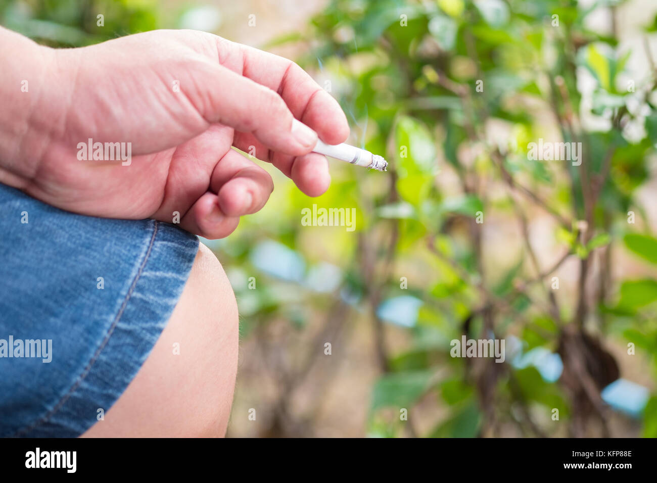 Close up of man hand with cigarette in his fingers on green background ...