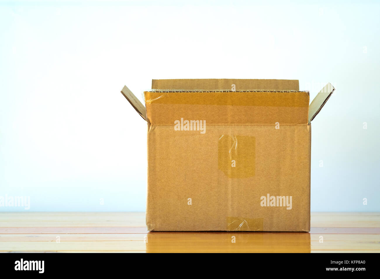 Empty opened old brown cardboard box for mock up on bright wooden table ...