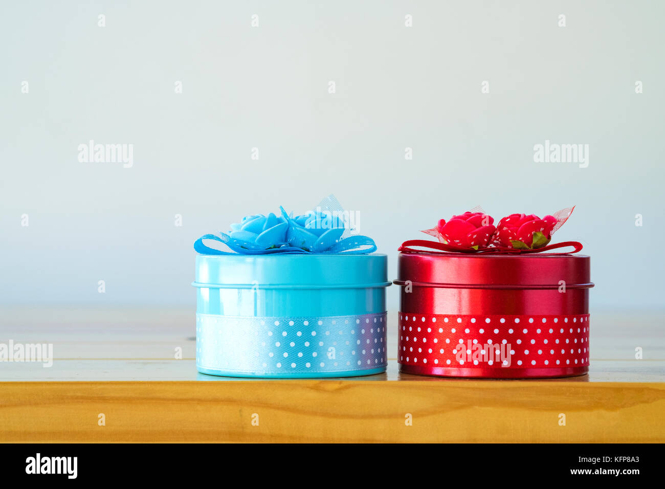 Round red and blue gift box with ribbon bow on bright wooden table with ...