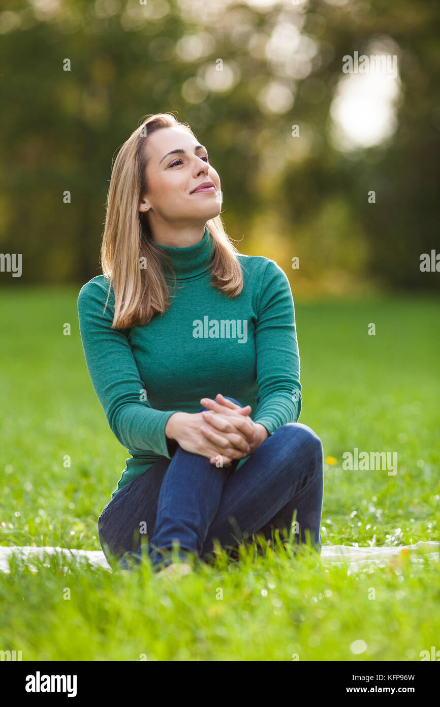 Happy woman sitting in park and enjoying nature Stock Photo - Alamy