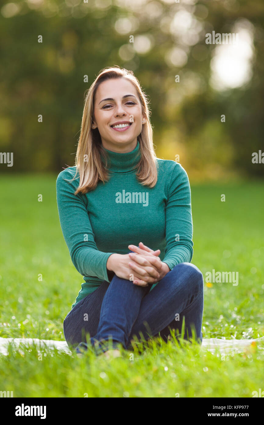 Happy woman sitting in park and enjoying nature Stock Photo - Alamy