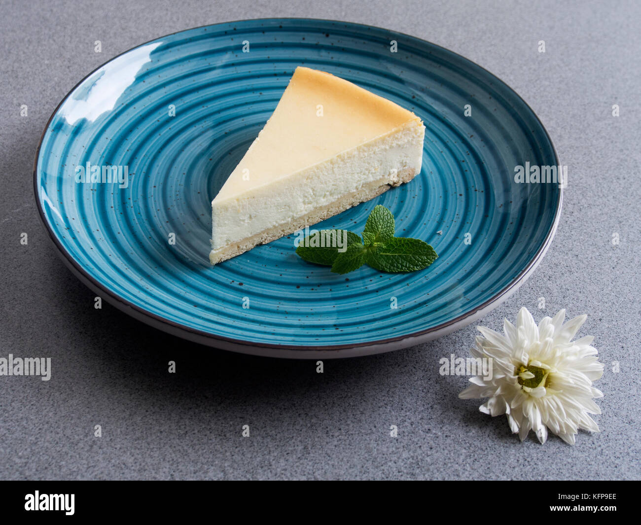 Slice of Cheesecake on blue plate on grey background Stock Photo - Alamy