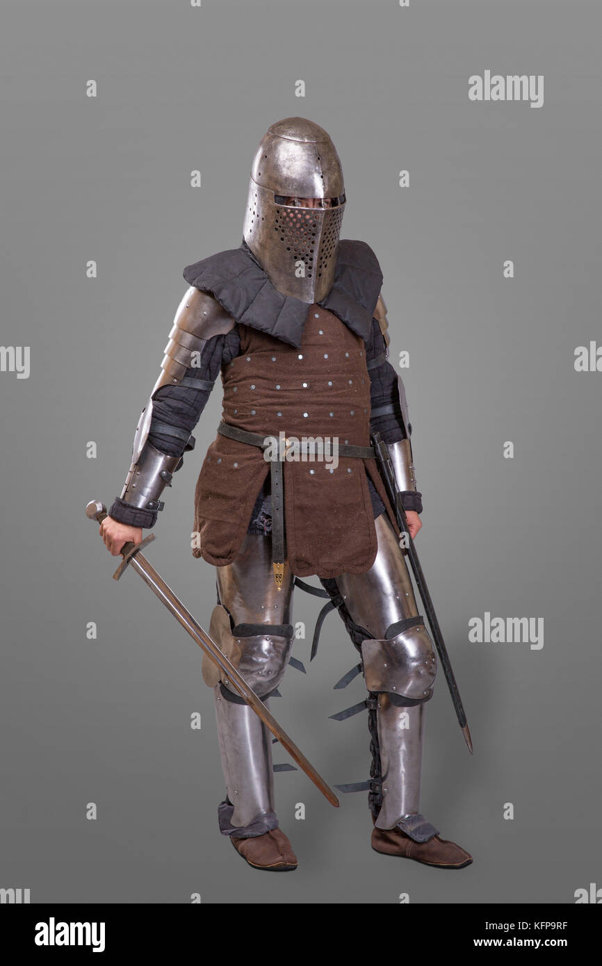 Armored knight in a helmet and with a sword isolated over gray ...