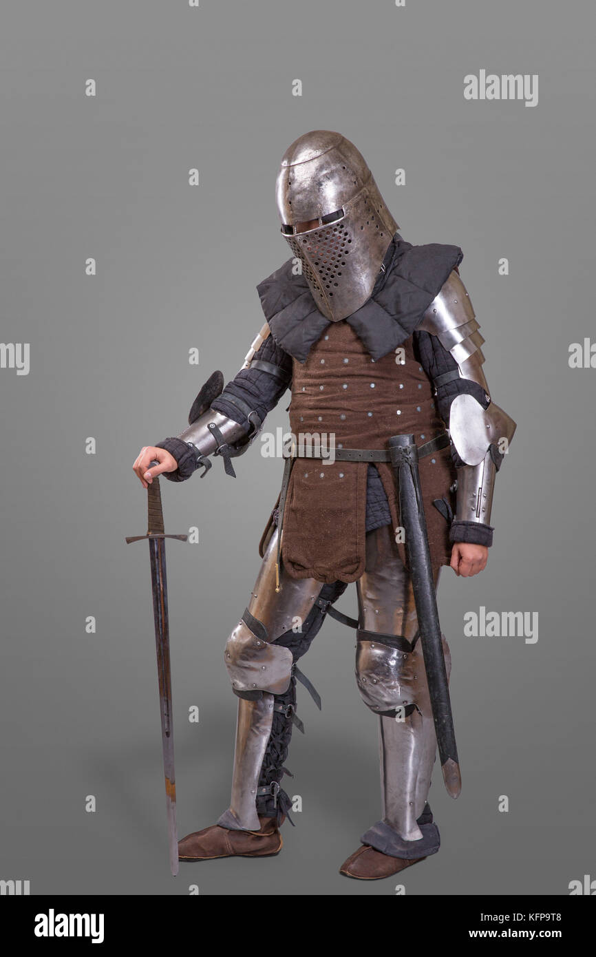 Armored knight in a helmet and with a sword isolated over gray ...