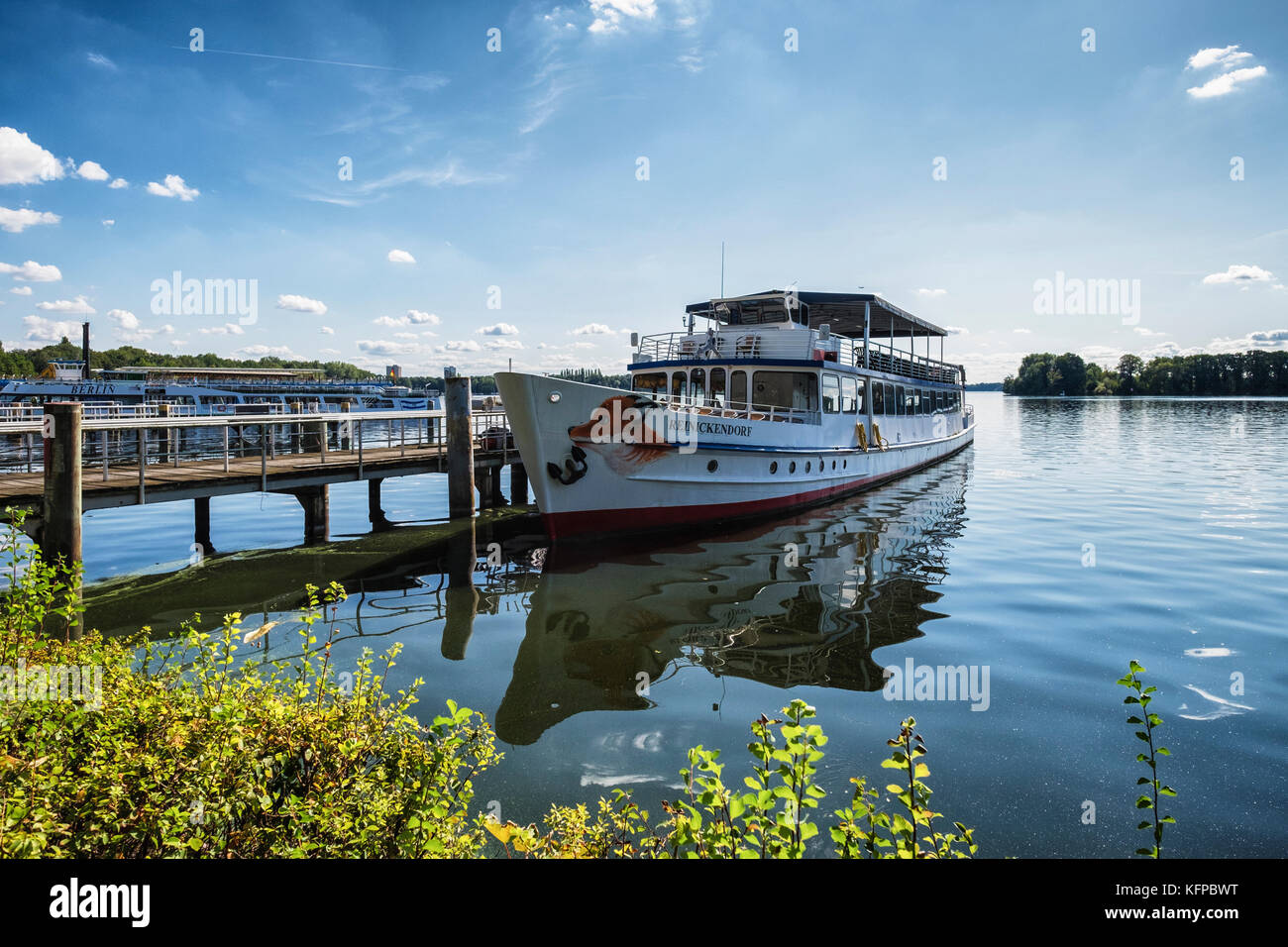 Berlin , Alt-Tegel.Pleasure boat moored at pier on calm and serene lake ...