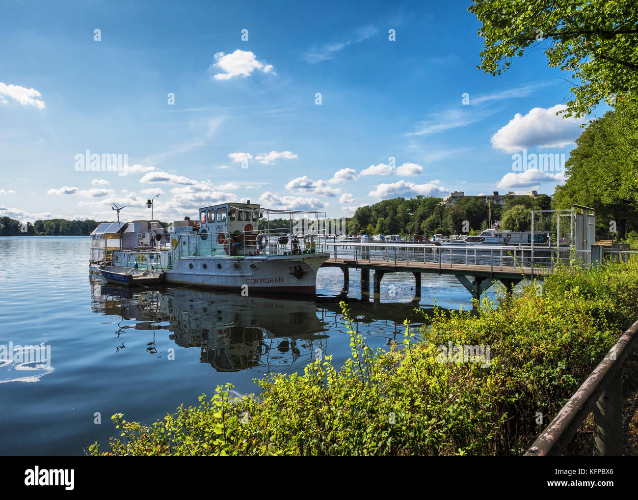 Berlin , Alt-Tegel.Pleasure boat moored at pier on calm and serene lake ...